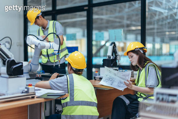 Trainees programing robotic arm in practical lesson at robotics academy ...