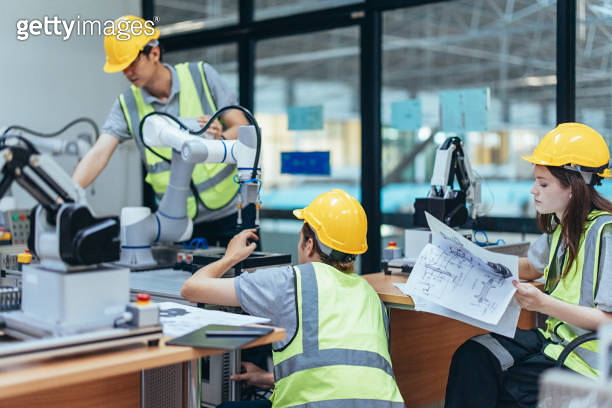 Trainees programing robotic arm in practical lesson at robotics academy ...