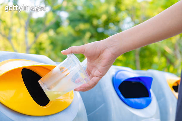 Please throw plastic cups into the bin. A man throws trash into a trash ...