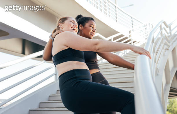 Two sportswomen having fun while standing at railing on the bridge ...