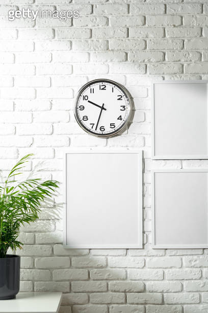 Minimalist White Wall Display With Clock and Empty Frames in a Modern ...