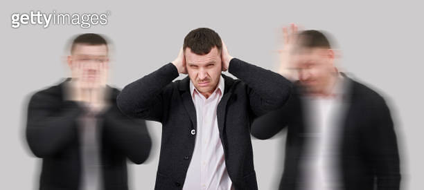 Man in focus expressing frustration surrounded by blurred figures ...