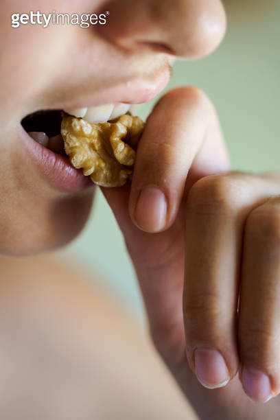 Crop unrecognizable teenage girl biting healthy walnut kernel ...