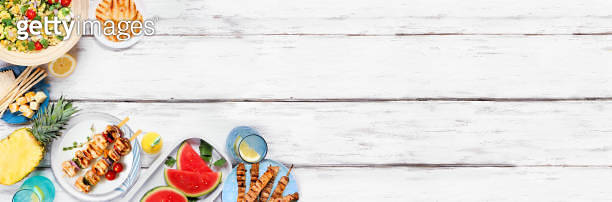 Summer food corner border with meat skewers, salad, fruit and snacks on ...