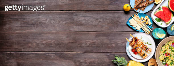 Summer food side border with meat skewers, salad, fruit and snacks on a ...