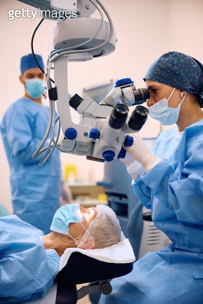 Medical expert using microscope while performing eye surgery at ...