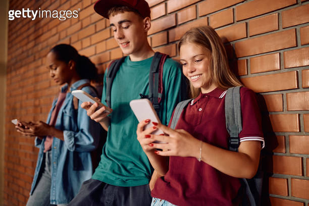 Group of happy teenagers using cell phones at high school 이미지 ...