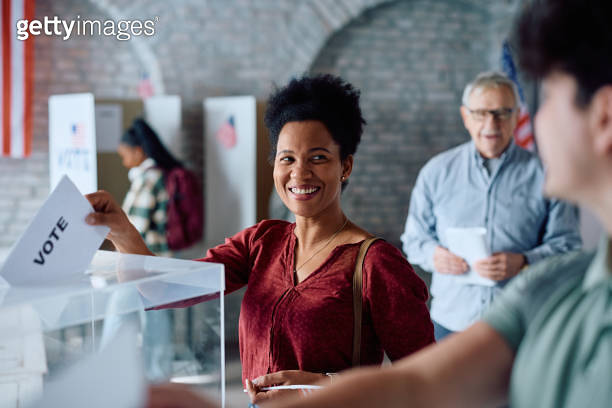 Happy black woman giving her vote at polling place during US elections ...