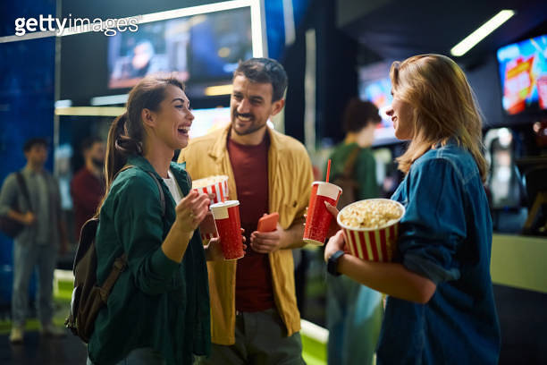 Cheerful woman having fun with her friends before projection in movie ...