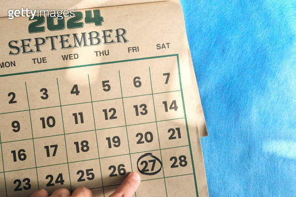Hand pointing on September 27 2024 date on calendar flat lay in blue ...