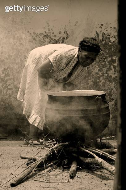 Old woman cooking in the fire with a 3 legged pot in rural KwaZulu ...
