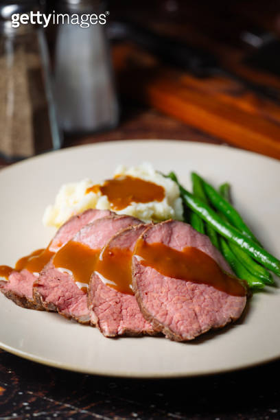 pouring brown gravy sauce on roasted beef 이미지 (2120834977) - 게티이미지뱅크