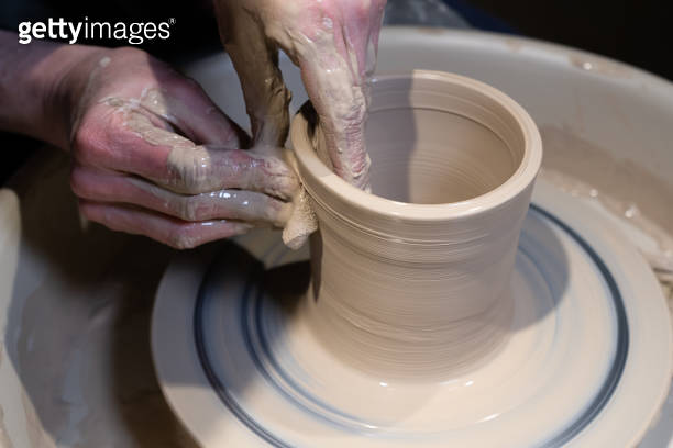 The hands of the master form a clay vessel from clay on a rotating ...