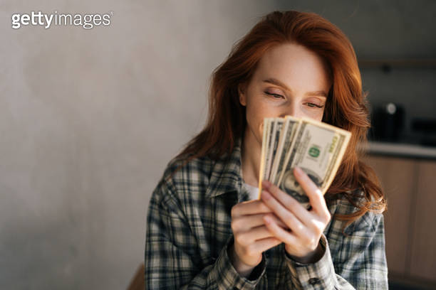 Closeup of cute young woman content with savings, counts money joyfully ...