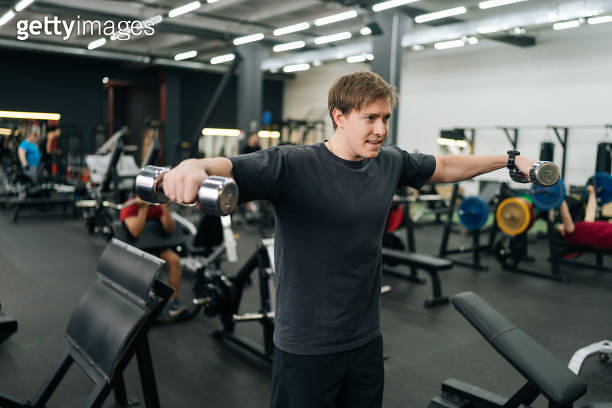 Portrait of motivated beginner sportsman hard time doing lateral arm ...