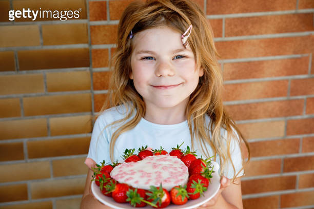Little preschool girl holding a heart birthday cake with strawberries ...