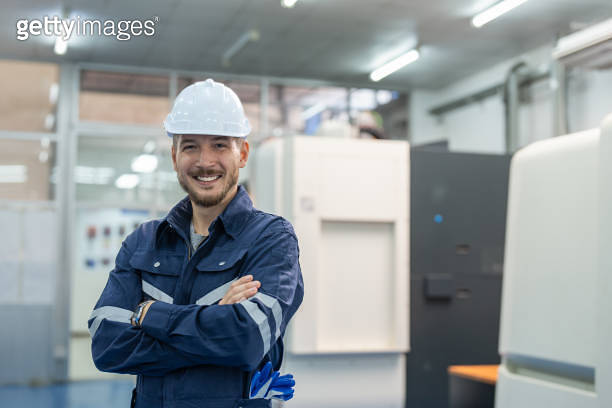 Male engineers standing and arms crossed at factory. Smiling technician ...