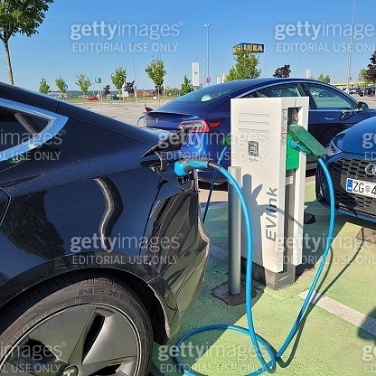A static shot of a solid black Tesla Model 3 dual motor charging at the ...