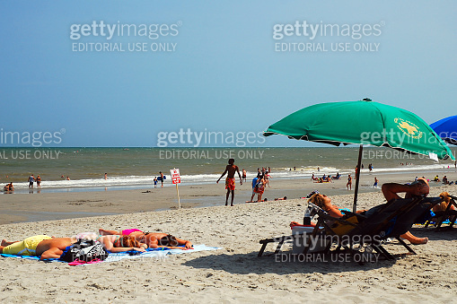 Folks sunbathing and taking shade at the shore 이미지 (2001507475) - 게티이미지뱅크