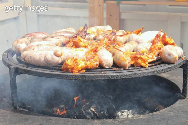 Fried sausages and chicken wings on barbecue grill in the village ...