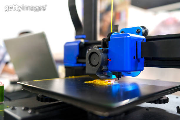 A close-up of a 3D printer at work, creating a three-dimensional object ...