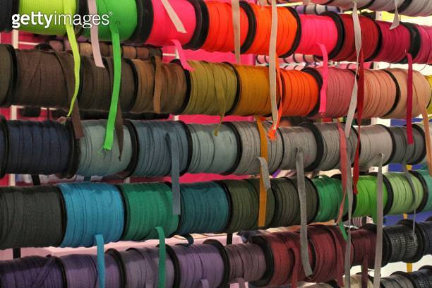 Bobbins with various colorful ribbons on counter in store. Needlework ...