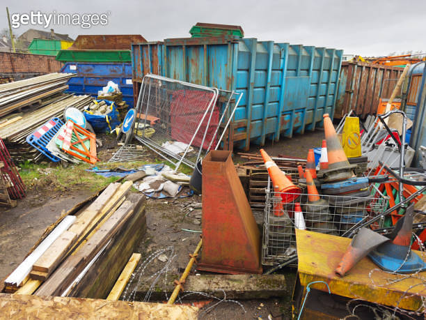 Junk yard and steel container with scrap metal, wood and traffic cones ...