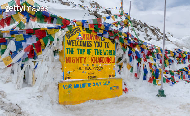 Yellow sign marking the summit of a major mountain pass in the ...