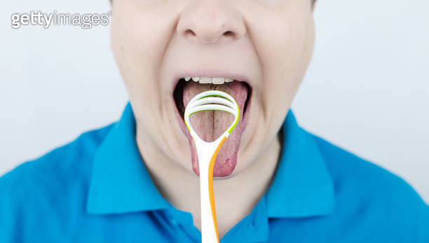 Tongue scraper. Man shows yellow plaque and then performs oral hygiene ...