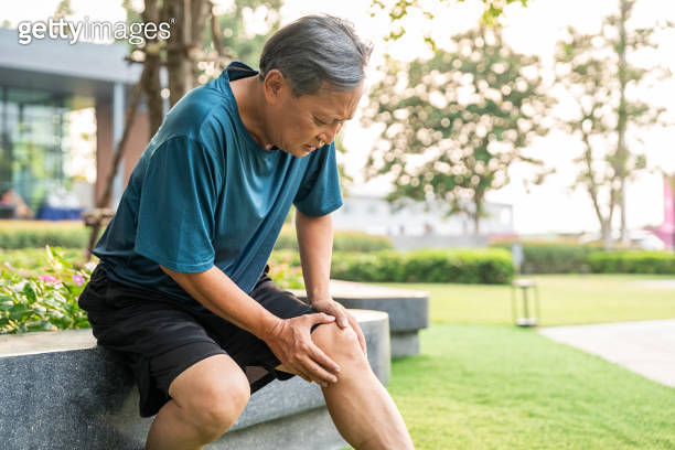 Mature man tired and leg pain during jogging at nature park. Runner has ...