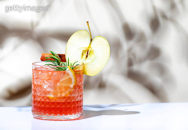 Red apple cocktail drink with vodka, liqueur, cinnamon, lemon with ...