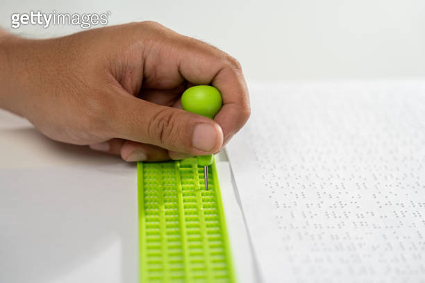 Close up Hand of a blind person writing some braille text on page paper ...