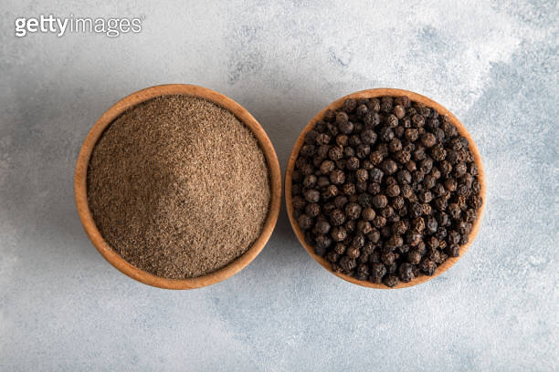 Ground black pepper on light blue background with black pepper grains ...