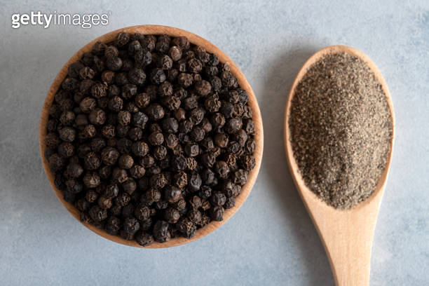 Ground black pepper on light blue background with black pepper grains ...