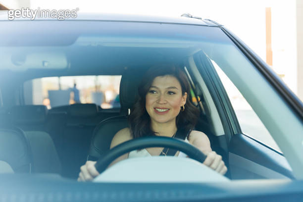 Confident woman smiling as she drives her car, prioritizing safety and ...