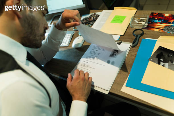 Point of view of investigator examining evidence and paperwork at his ...