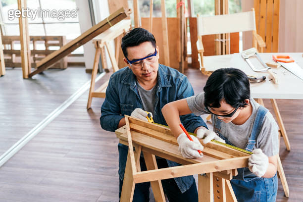 Close-up carpenter hands wearing work gloves draw the cutting line with ...