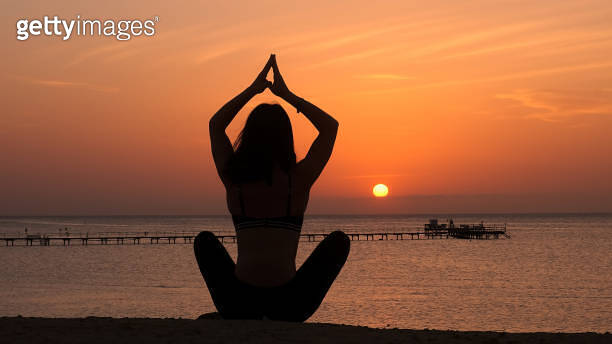 Strong, confident, beautiful woman under the sunset sky on the ocean. A ...
