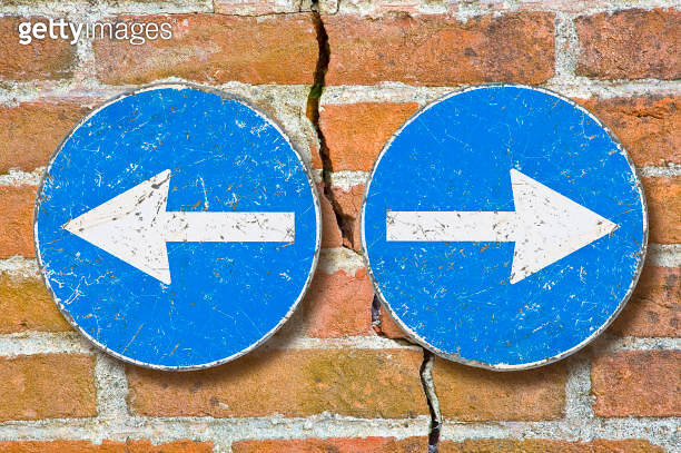 Arrow signs against a brick wall indicating to go left and right ...