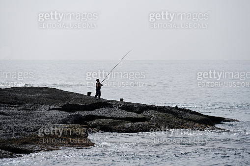 Adult female angler casting her line into the sea on the Atlantic coast ...