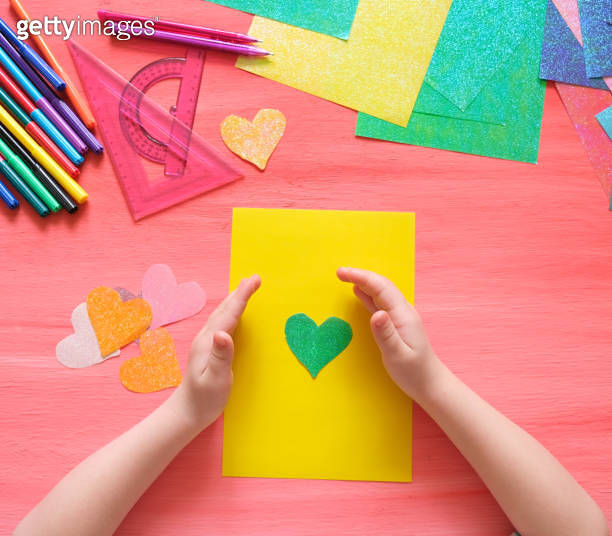 Child making greeting card, crafts from paper. Flowers and hearts as ...