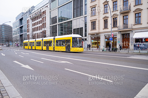 yellow tram driving down city street in Berlin in front buildings ...