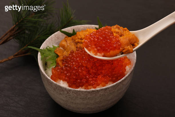 A bowl of rice topped with sea urchin and salmon roe, seafood ...
