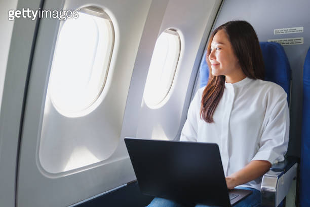 Portrait image of a woman working on laptop computer while traveling on ...