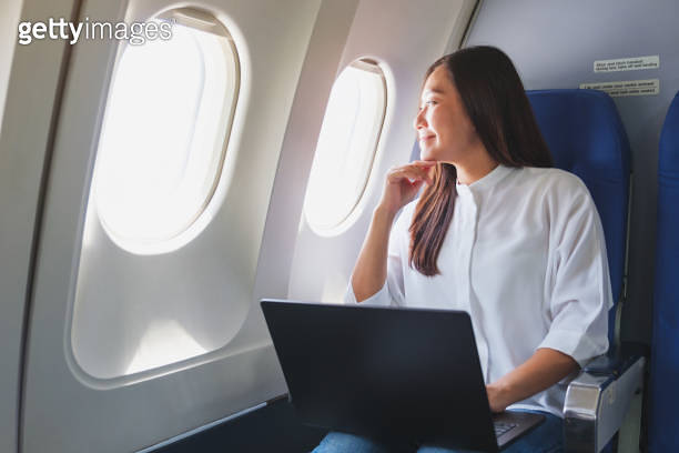 Portrait image of a woman working on laptop computer while traveling on ...