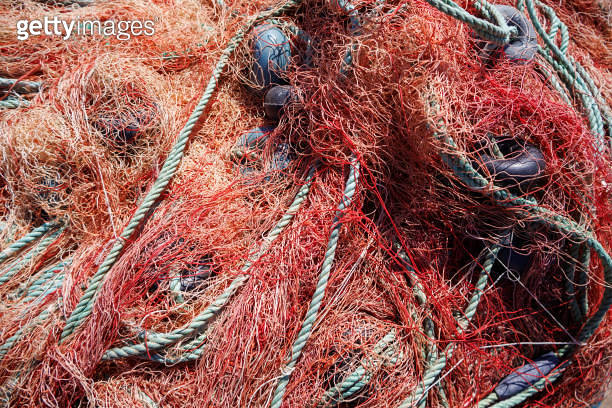 Fishing nets in the port. Fishing nets are laid out on the floor. Red ...
