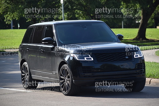 A portrait of a black Land Rover Range Rover SUV near a nature reserve ...