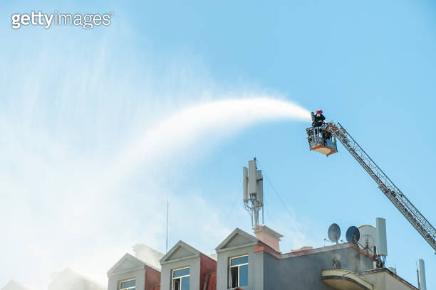 Firefighters extinguish burning house using extended ladder equipped ...