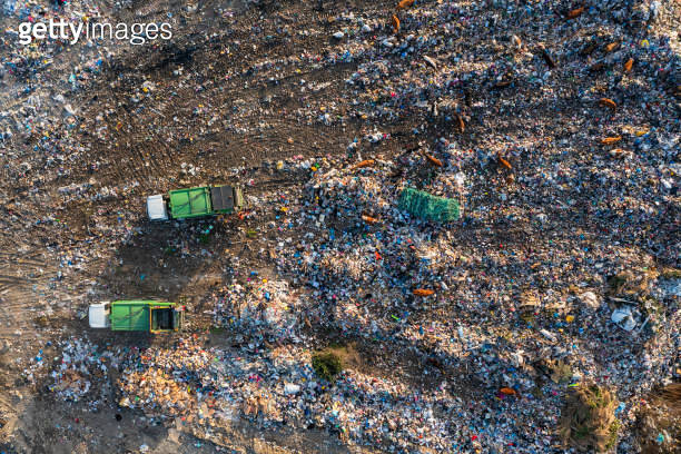 Aerial top down view of garbage trucks unload pile of waste at landfill ...