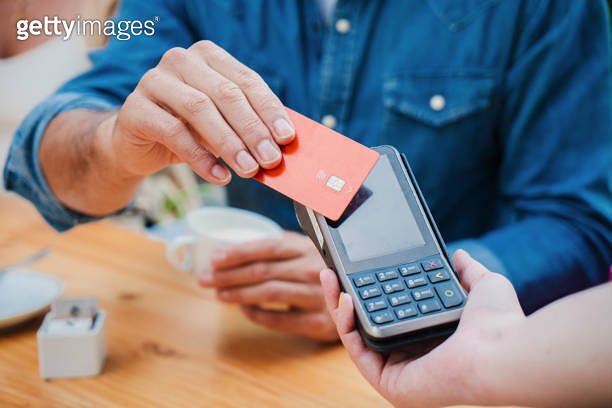 Male customer paying a bill with a contactless credit card in a ...